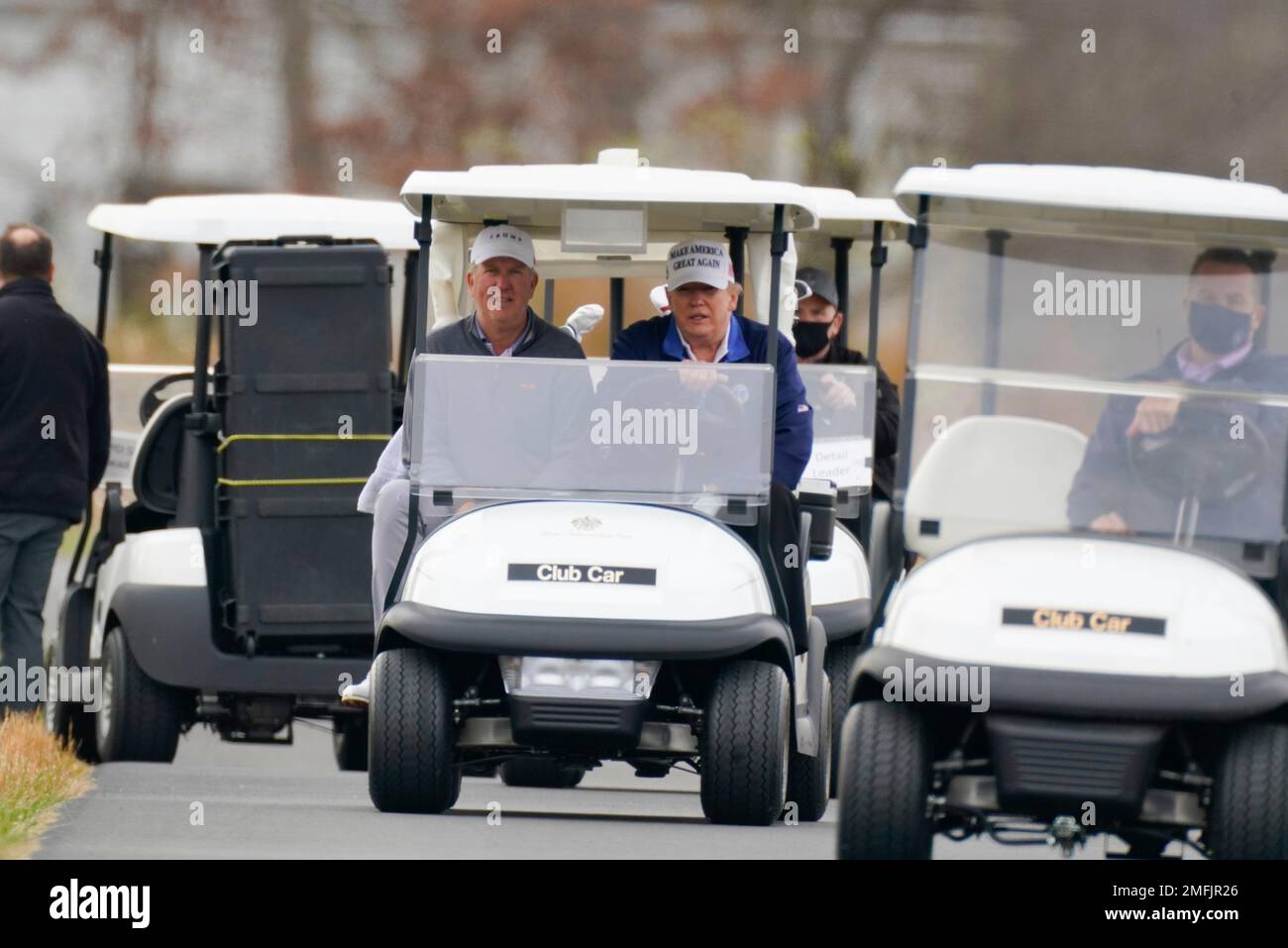 President Donald Trump, center, drives a golf cart as he golfs at Trump ...