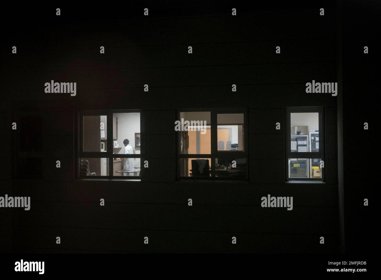 A hospital worker is pictured through a window at night in the La ...