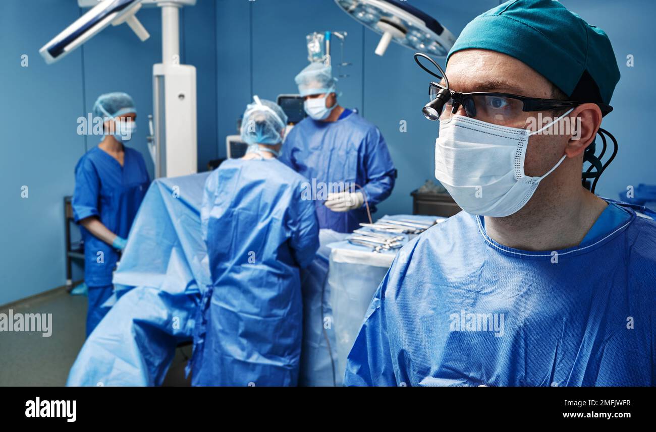 Teamwork in surgical department. Male surgeon wearing PPE standing in ...