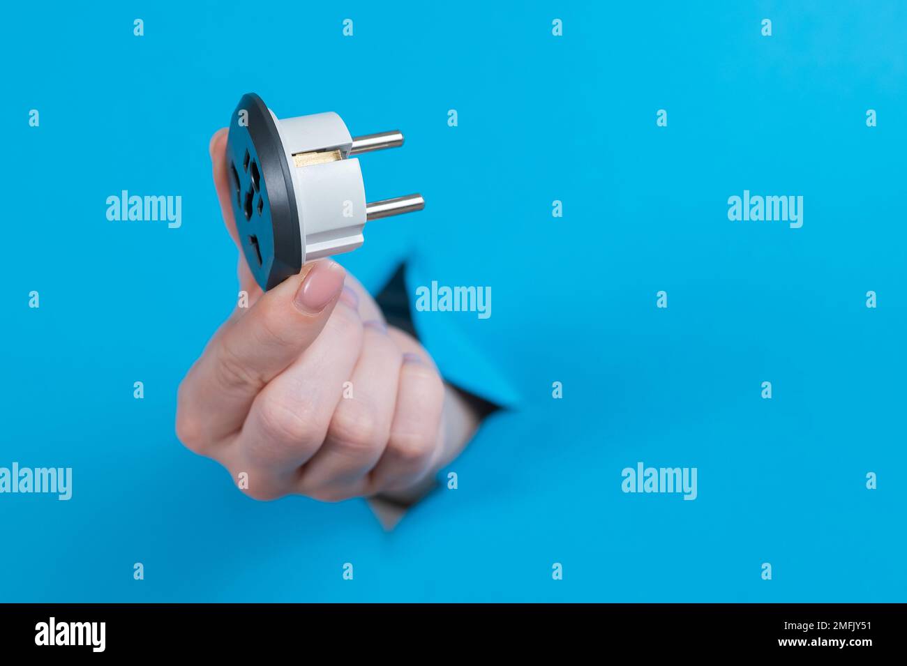 A woman is holding an outlet adapter. A woman's hand sticks out through ...
