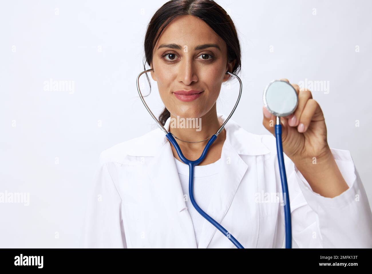 Woman doctor with stethoscope in hand in medical gown on white nurse background, consequences of ...