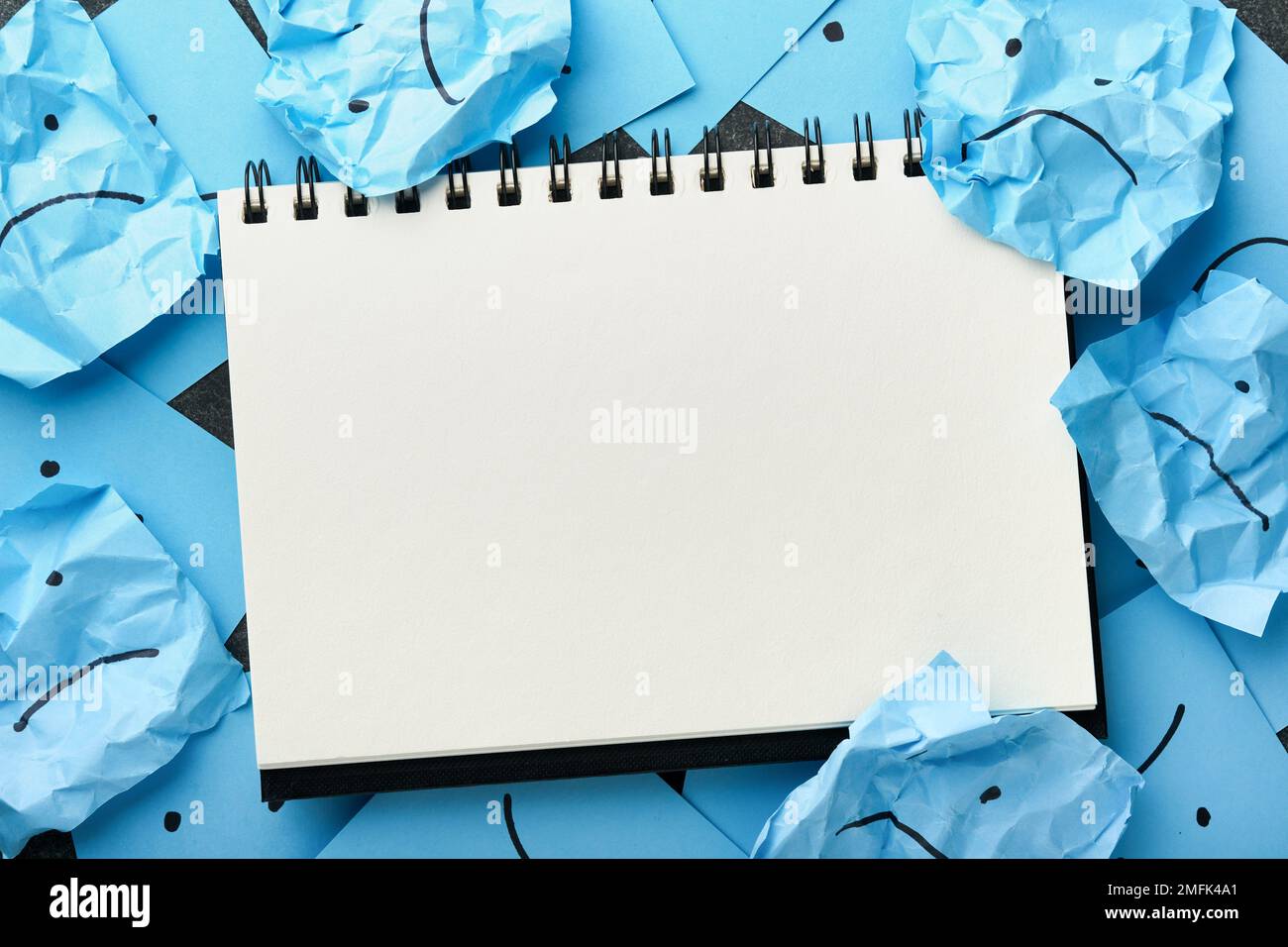 Blue crumpled sticky notes blank with drawing sad face on black ...