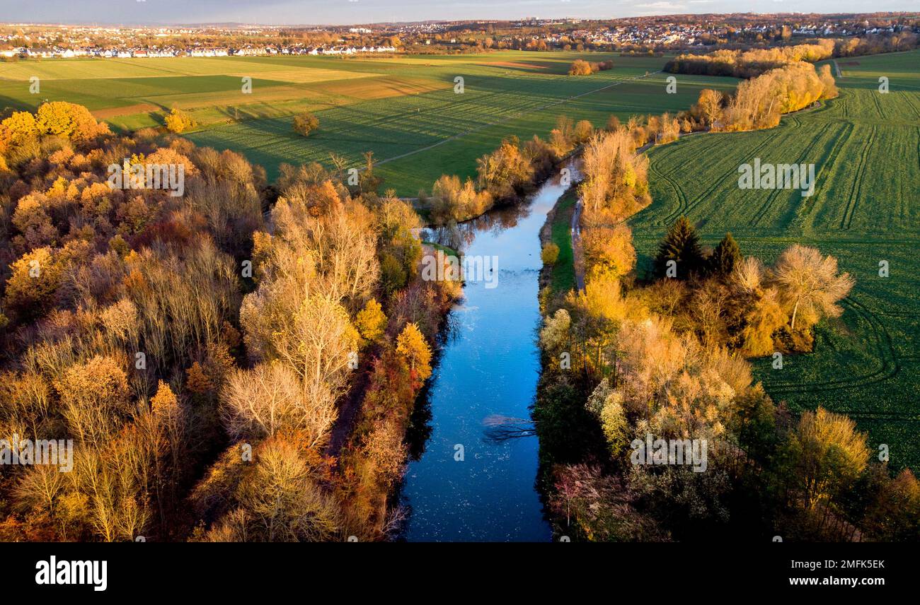 The small Nidda river flows between trees illuminated by the evening ...