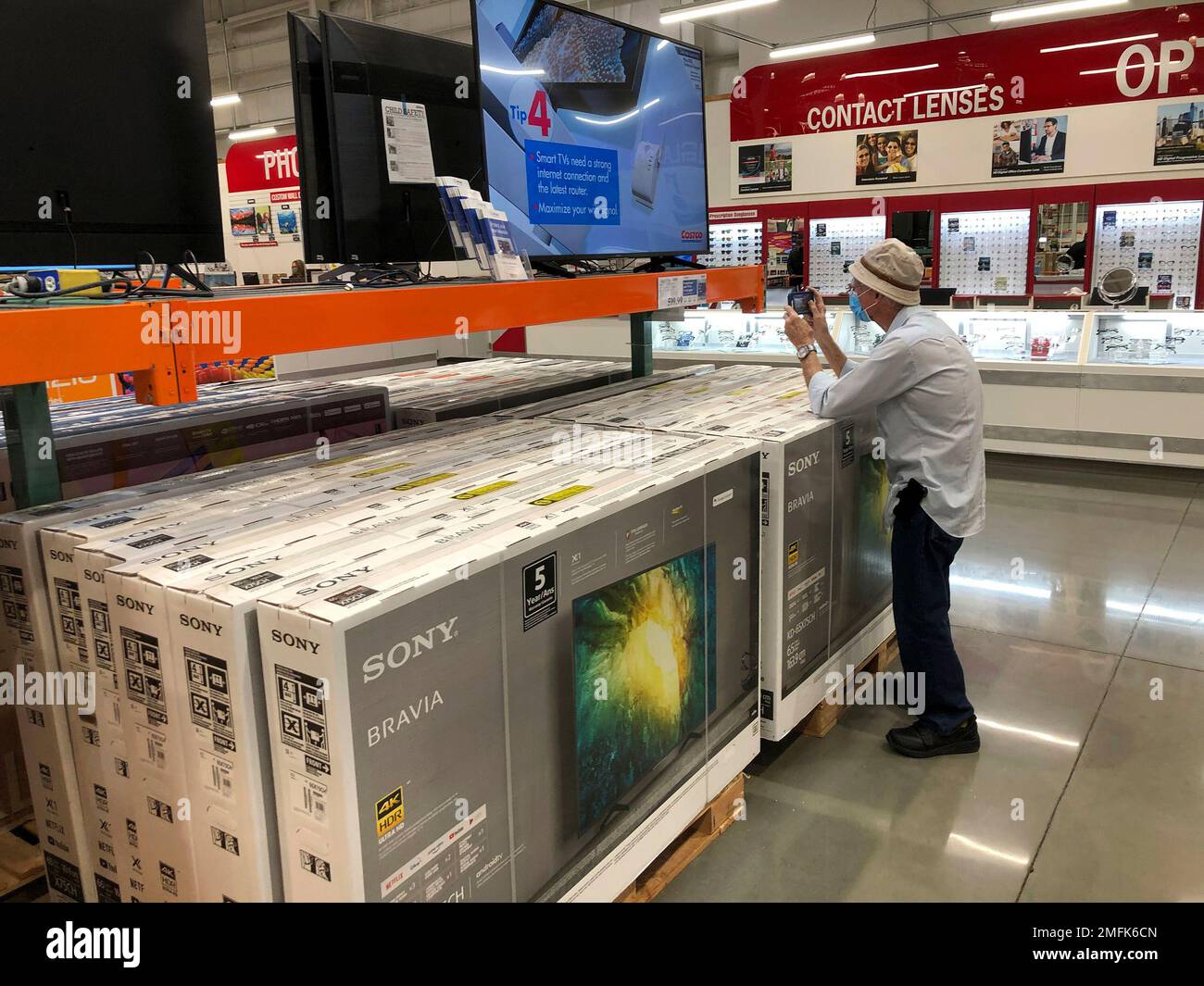 A shopper uses his mobile device to photograph a big-screen television ...