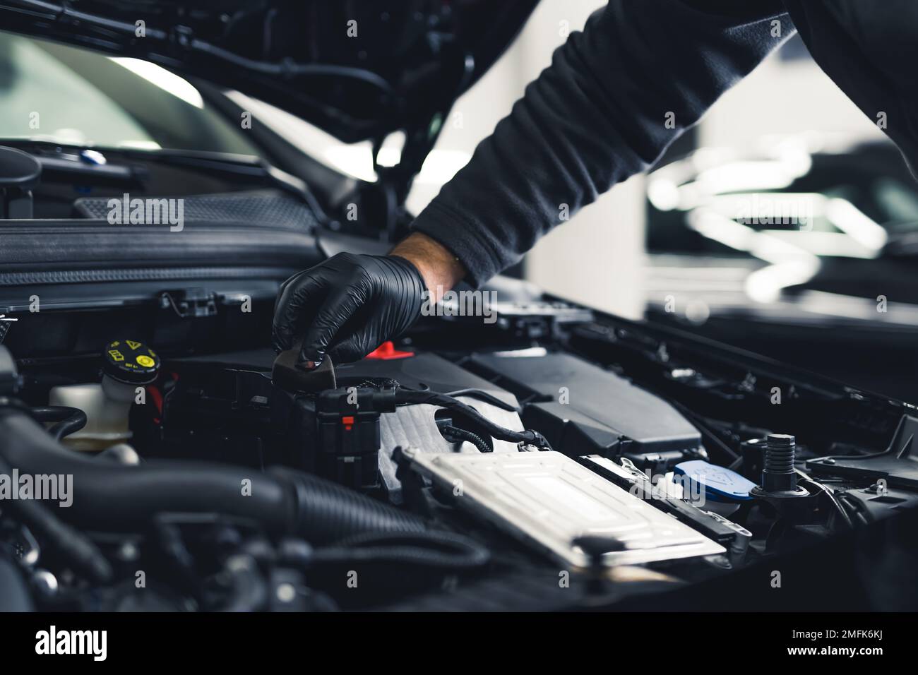 Close-up shot of unrecognisable man wearing black glove inspecting car engine and interior of ...