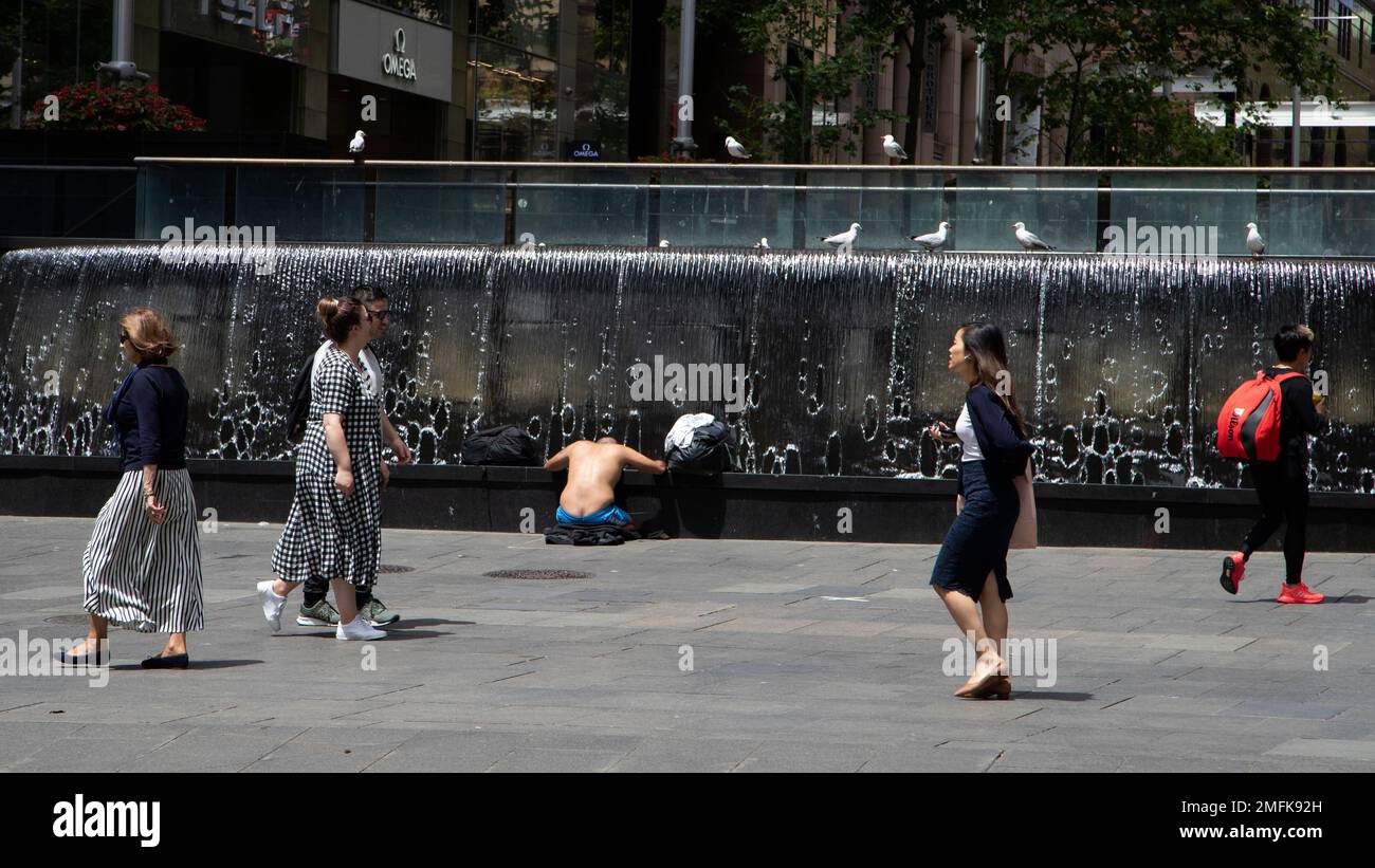 A man kneels at the foot of a fountain in the central business district ...