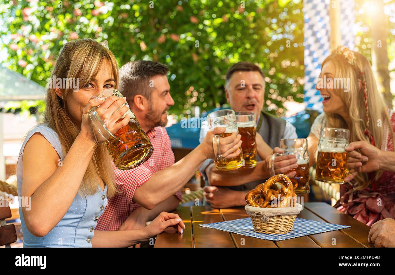 Friends, three men, two women, sitting in beer garden with beer glasses ...