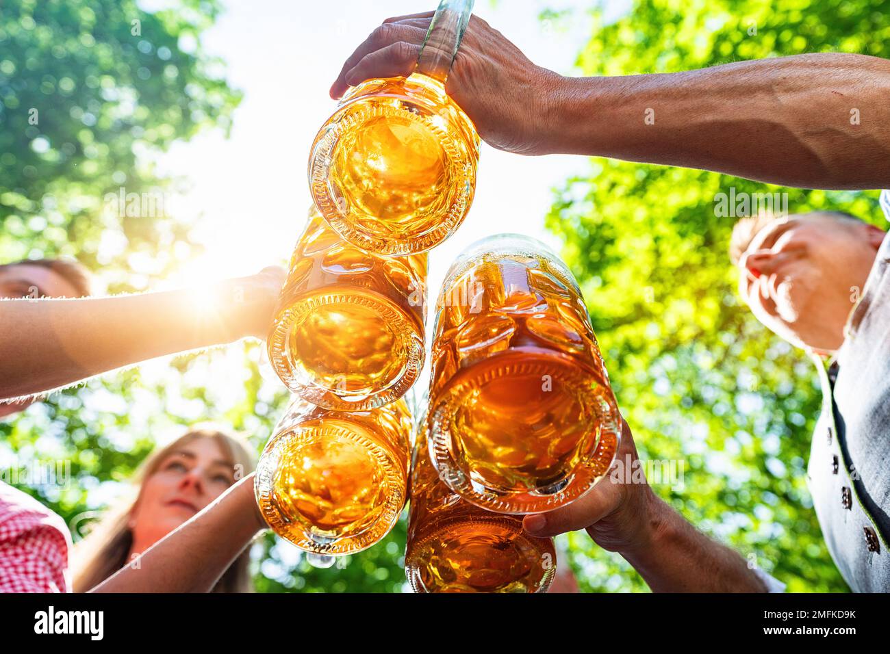 Group of happy Bavarian friends drinking and toasting beer at ...