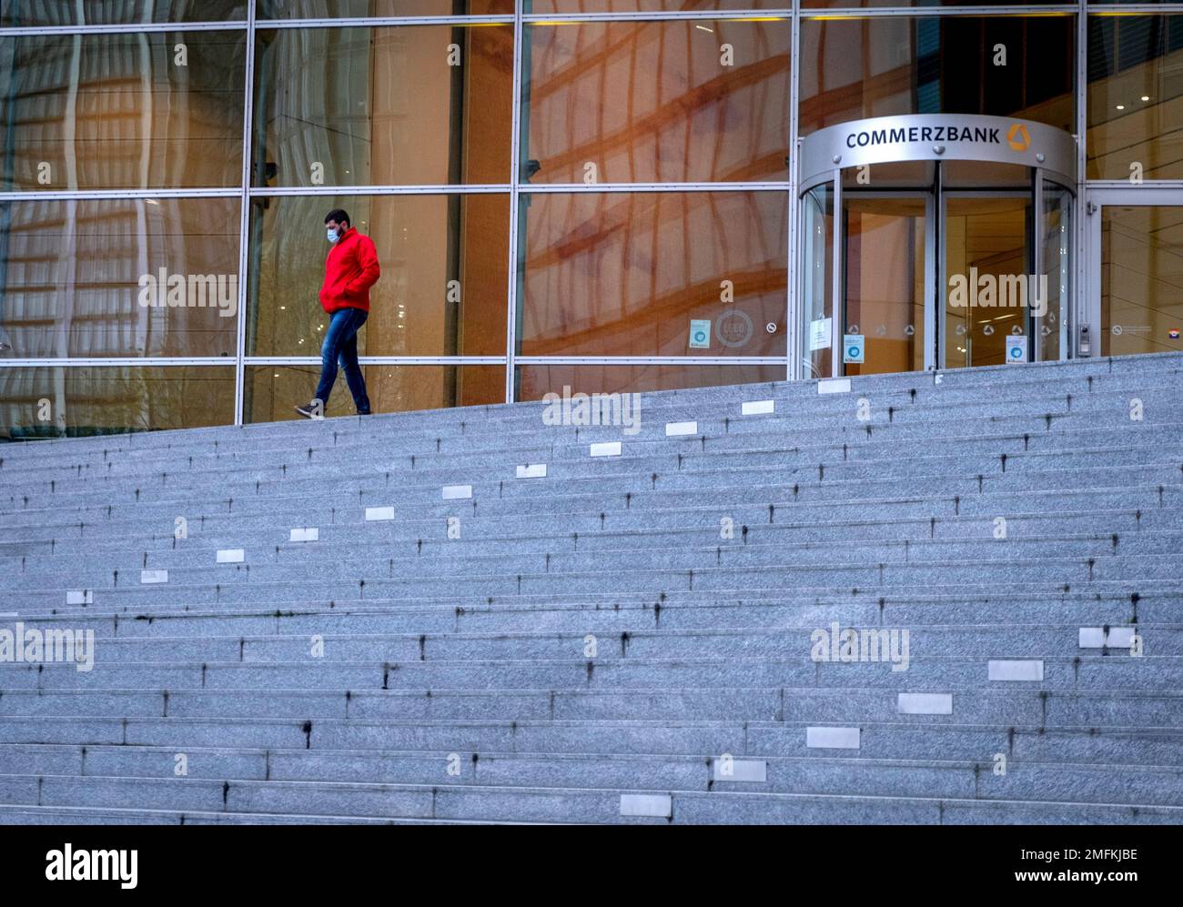 A man wearing a face mask walks down the stairs of the Commerzbank in ...