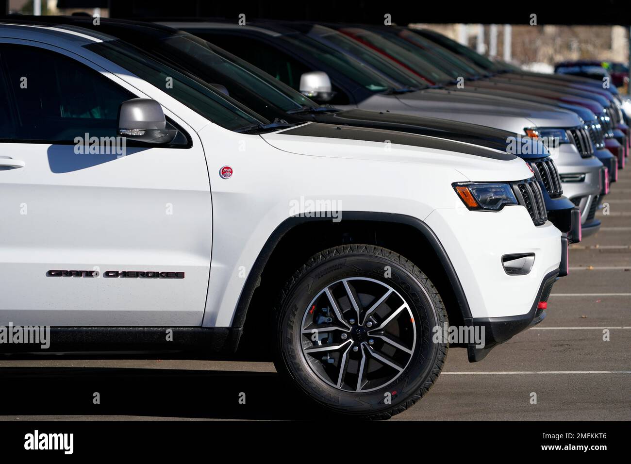 A long row of unsold 2021 Grand Cherokees sits at a Chrysler/Jeep ...