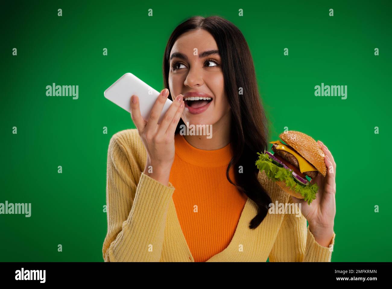 happy woman holding tasty burger and sending voice message on ...