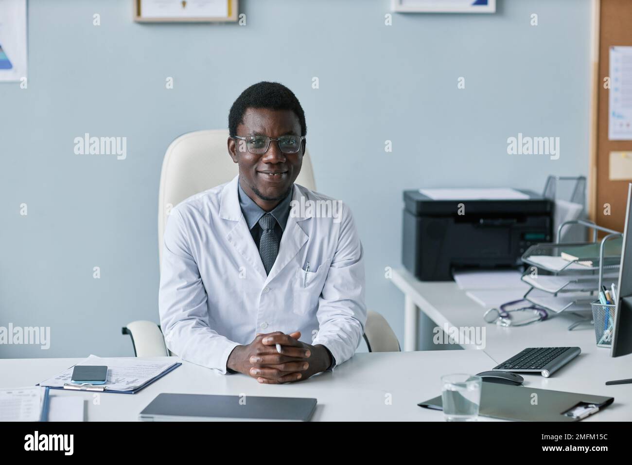Minimal front view portrait of smiling black doctor looking at camera ...