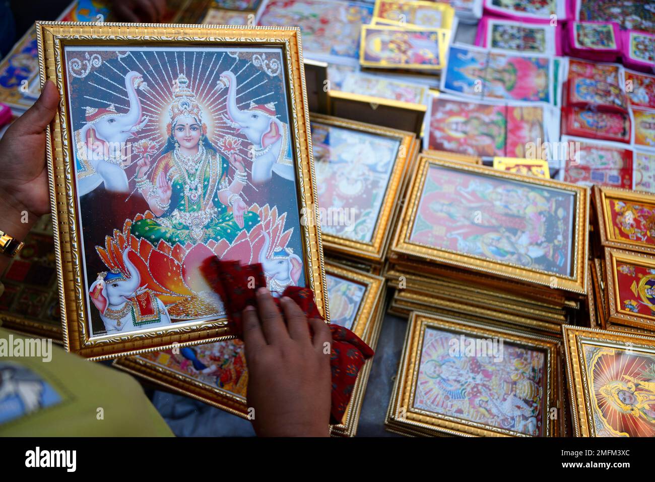 A Nepalese vendor cleans a photograph of goddess Laxmi as she waits for ...