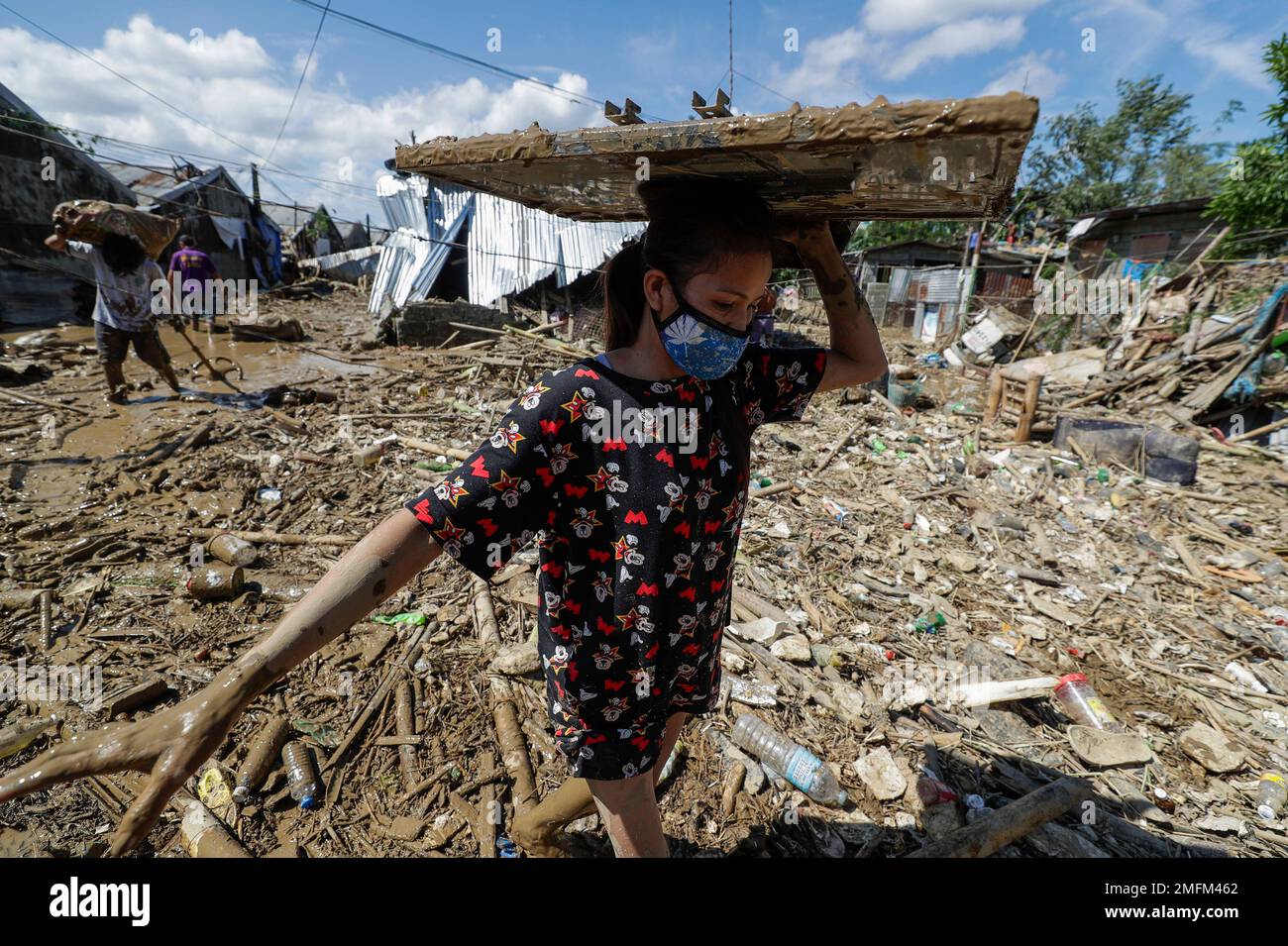 A resident carries a television across debris and floods at the typhoon ...