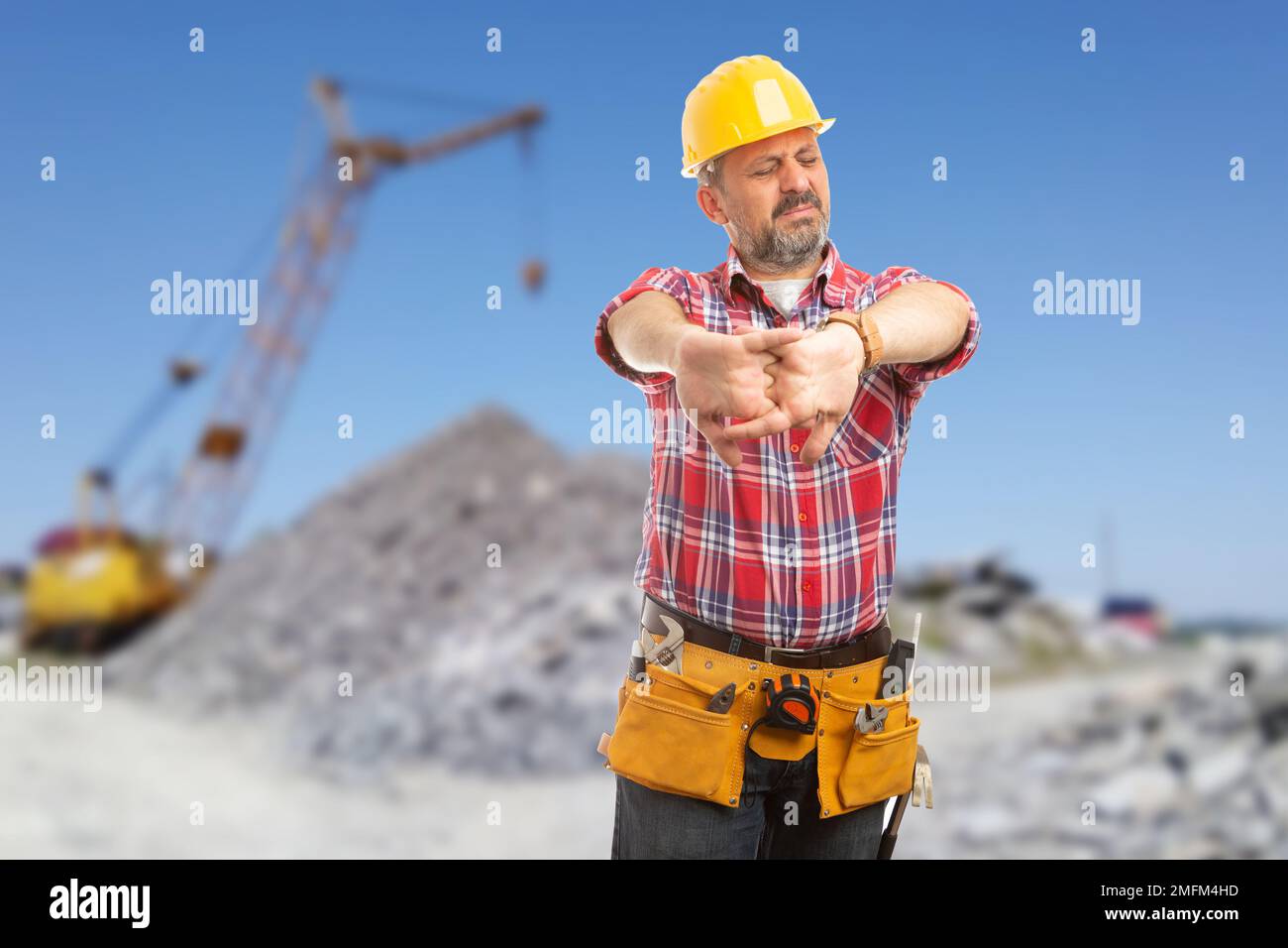 Tired adult man working in constructions stretching hands as hard ...