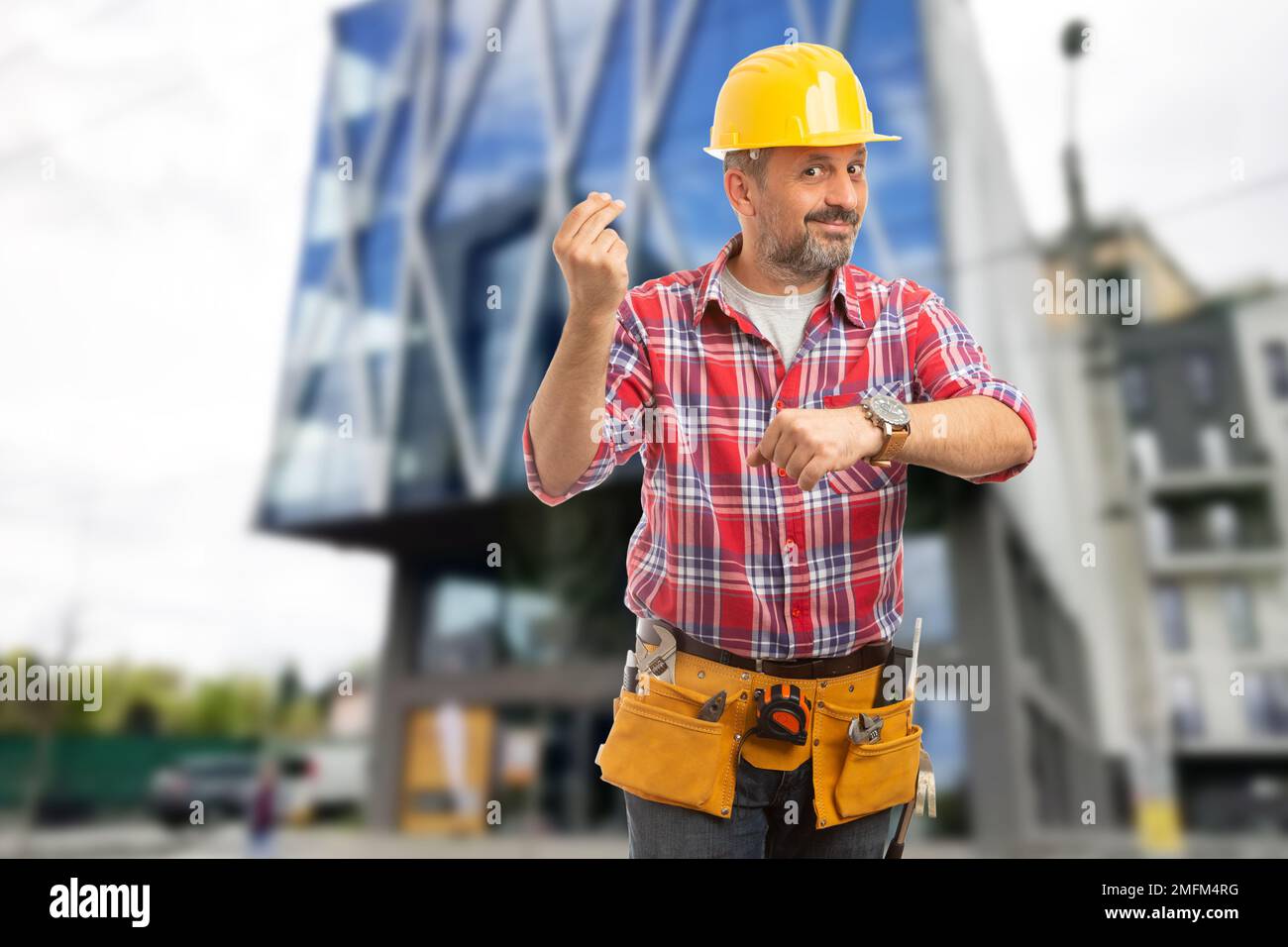 Smiling worker making time is money gesture and showing his watch as ...