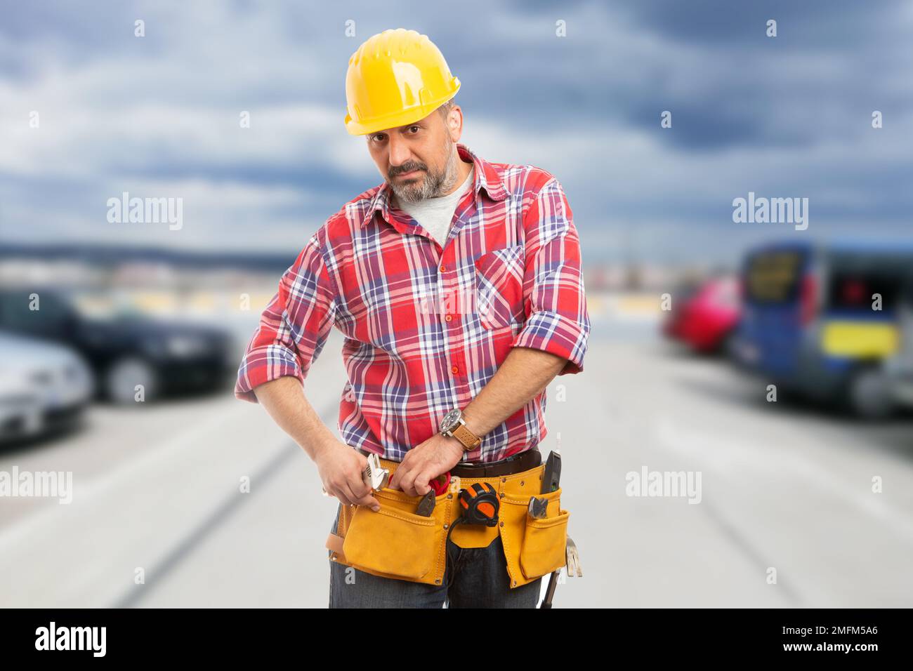 Worker man grabbing wrench from his tools pouch as working day concept ...