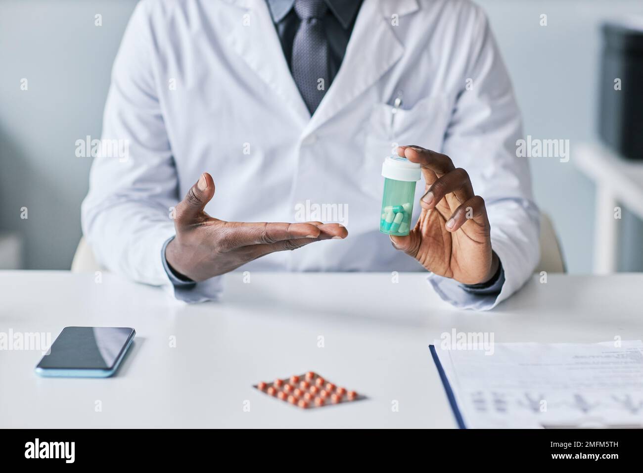 Minimal closeup of black doctor holding bottle of pills and pointing ... Minimal closeup of black doctor holding bottle of pills and pointing ...