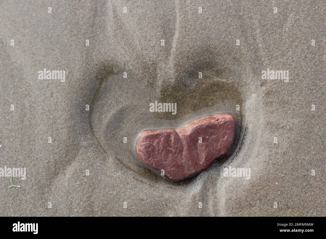 red rock isolated on the sand inside a heart shaped indent (Inch Beach ...