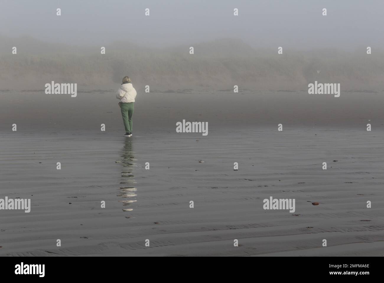 Woman thinking at the beach - reflected jarringly in the sand Stock ...