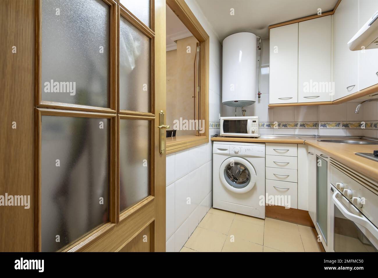Corner kitchen with white furniture, hatch window to the living room ...
