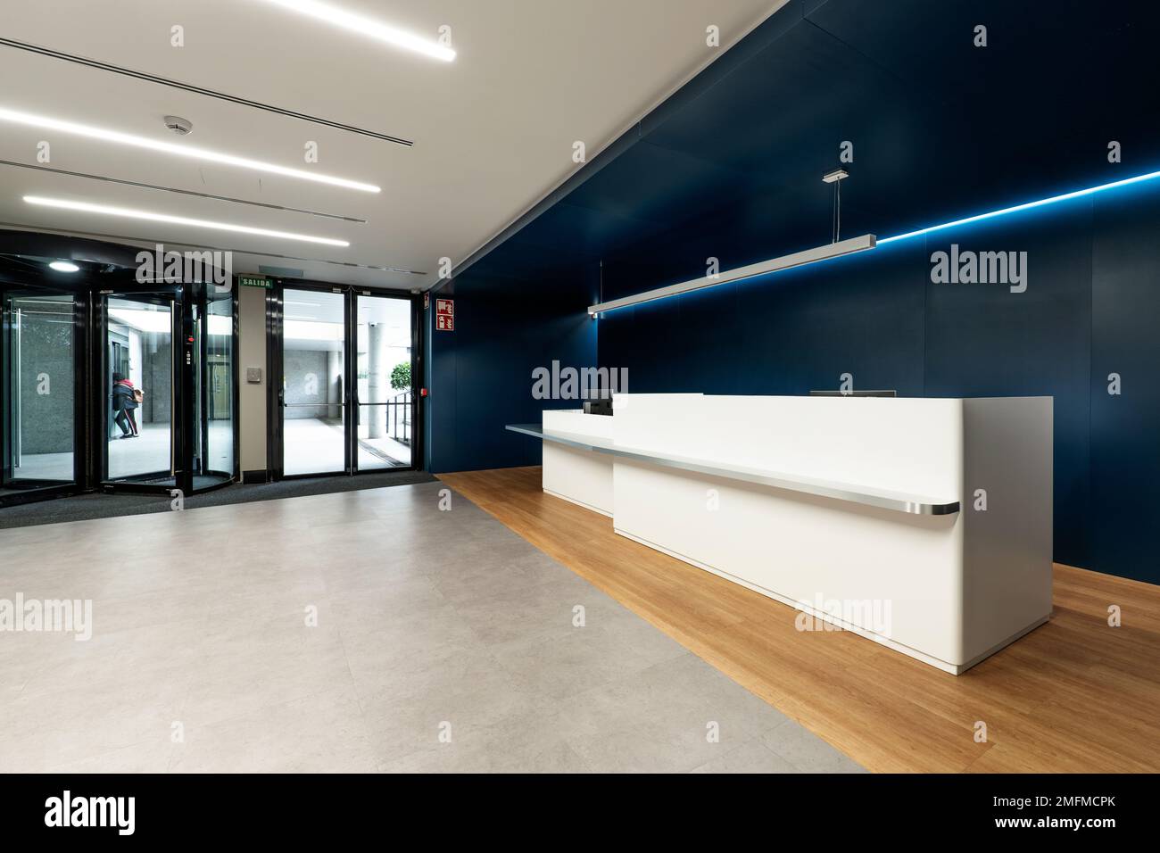 White reception desk in a blue cubicle with a wooden floor next to a ...