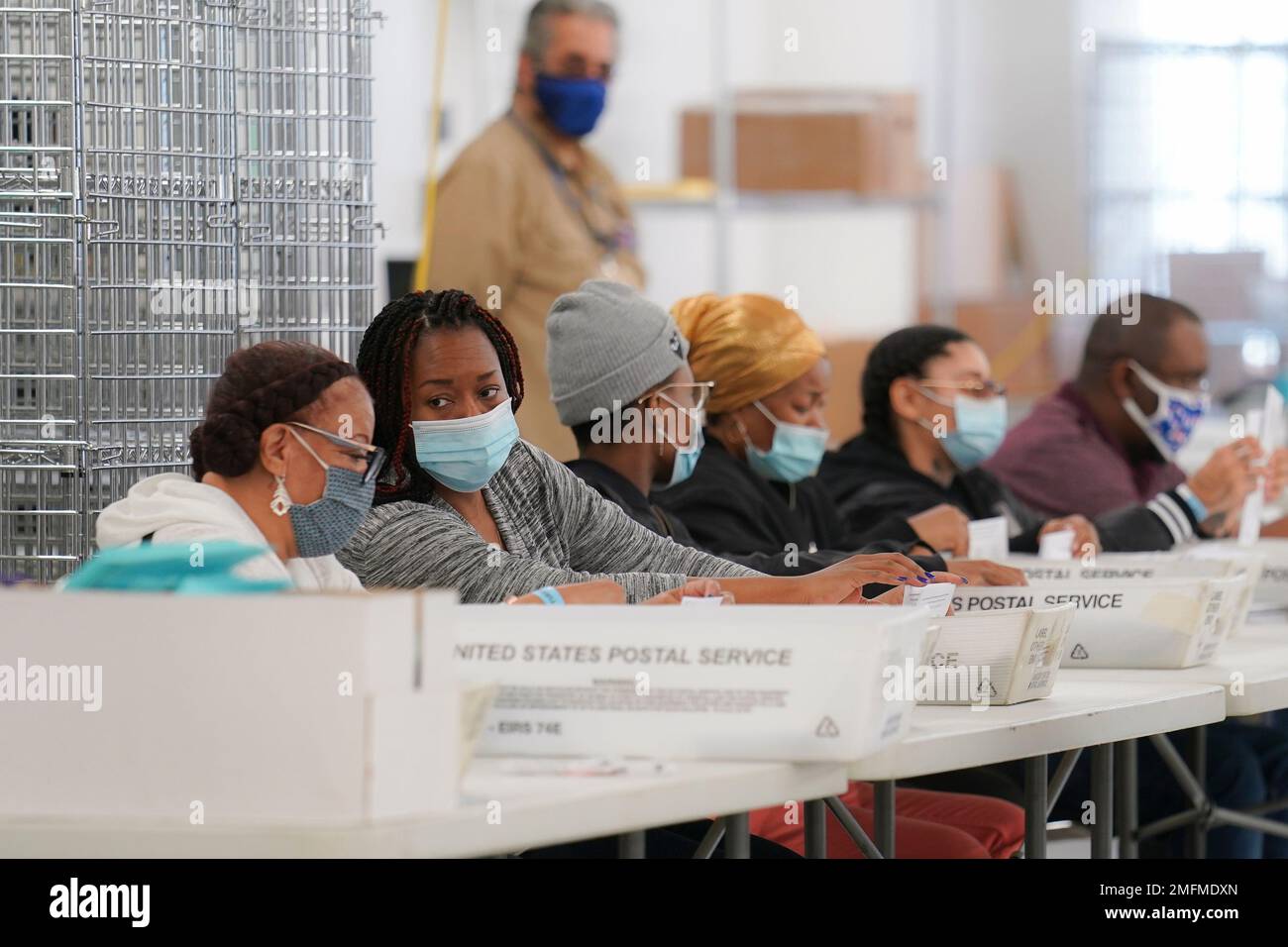 Polling workers inspect and count absentee ballots, Tuesday, Nov. 10 ...