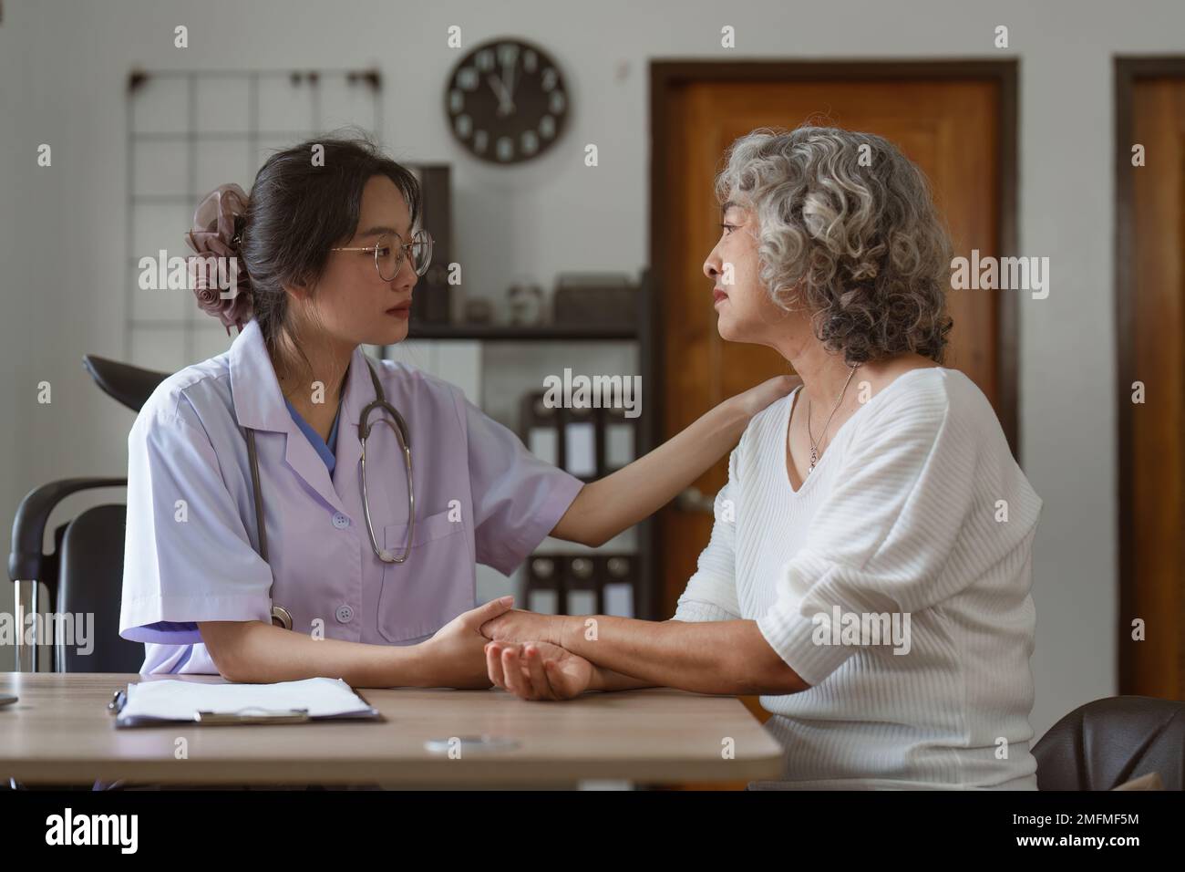 Doctor talking with elderly asian woman. Female primary care physician ...