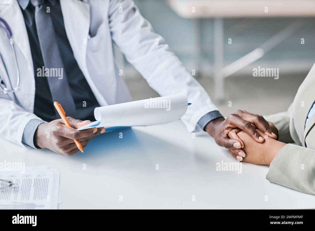 Close up of caring doctor holding hands with female patient during ...