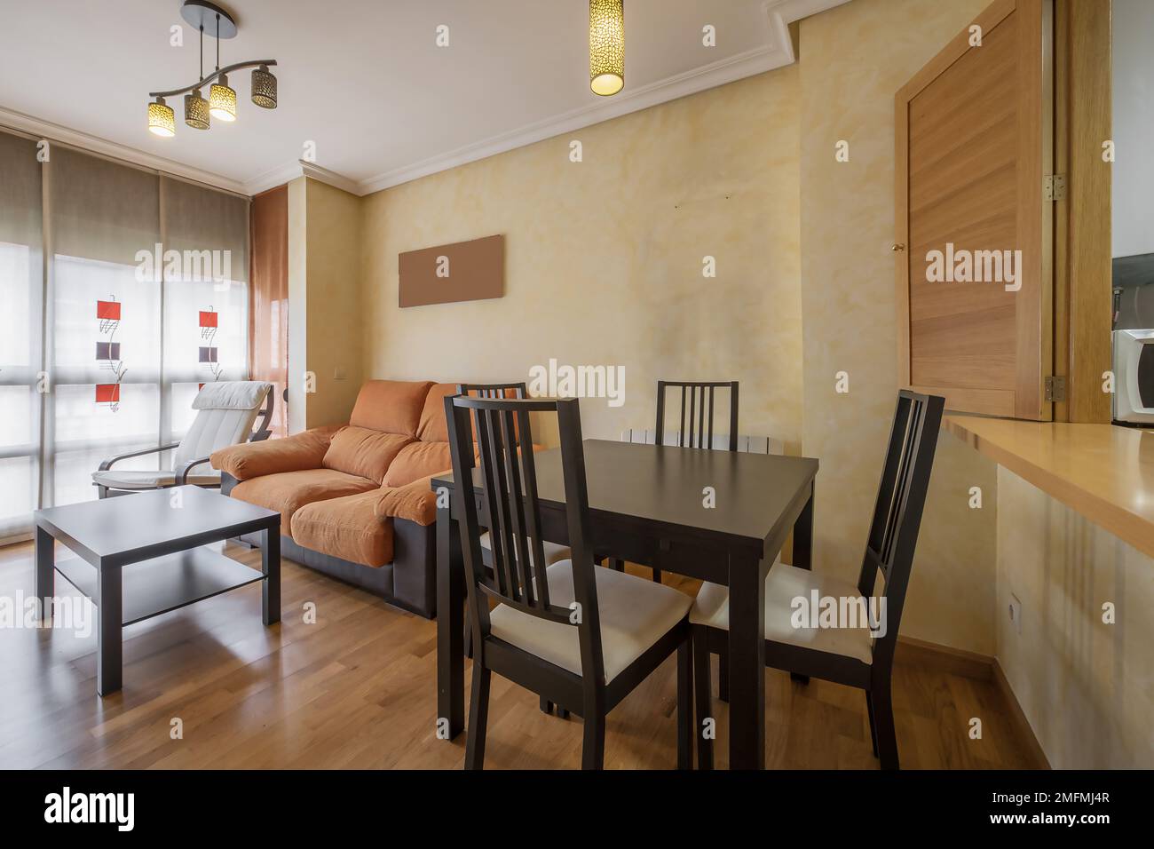 Small living-dining room with a square wooden table next to a serving ...