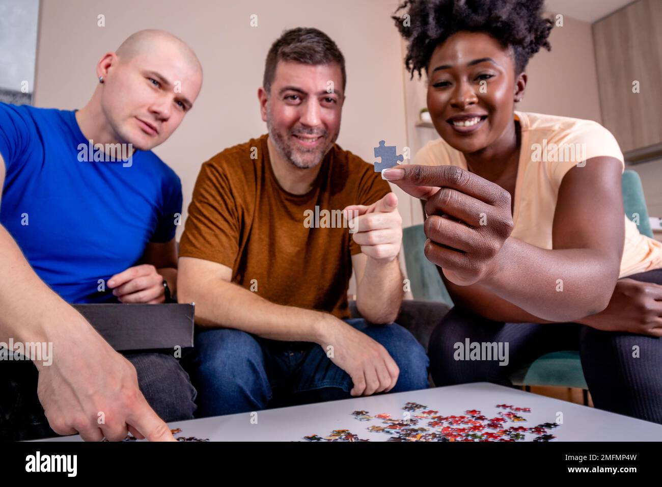 Friends playing jigsaw puzzles at home. Solving problems and putting ...