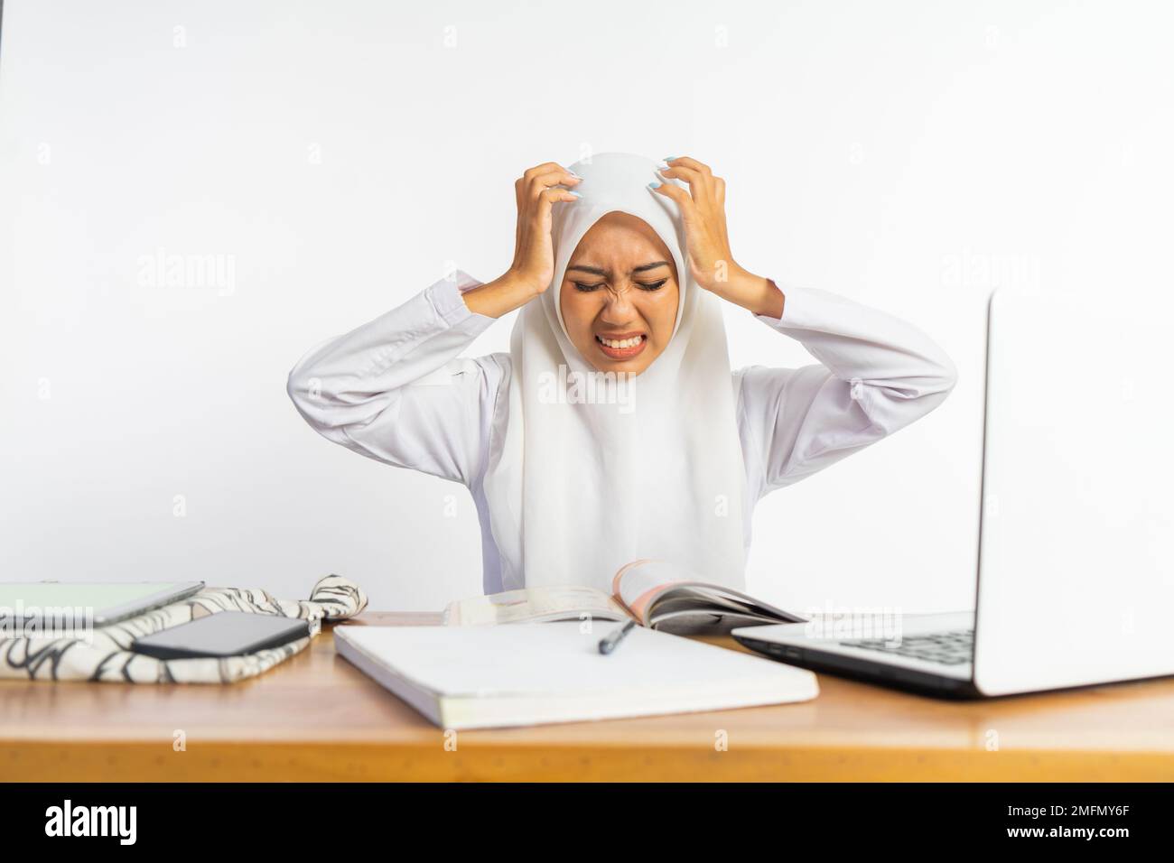 veiled high school student at desk in stress using laptop Stock Photo ...