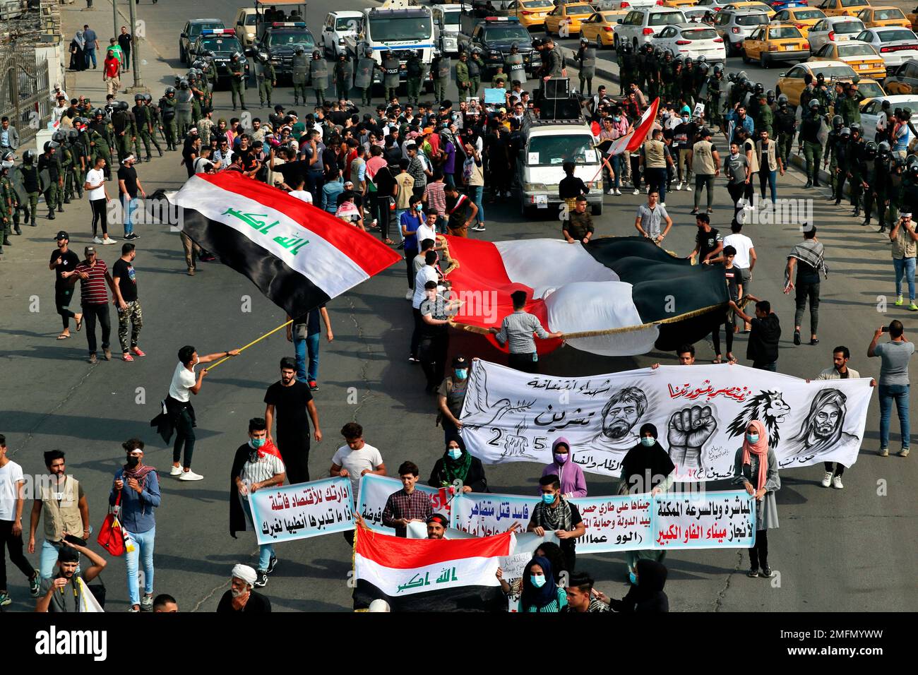 Protesters hold Iraqi flags as they head towards Tahrir Square during a ...