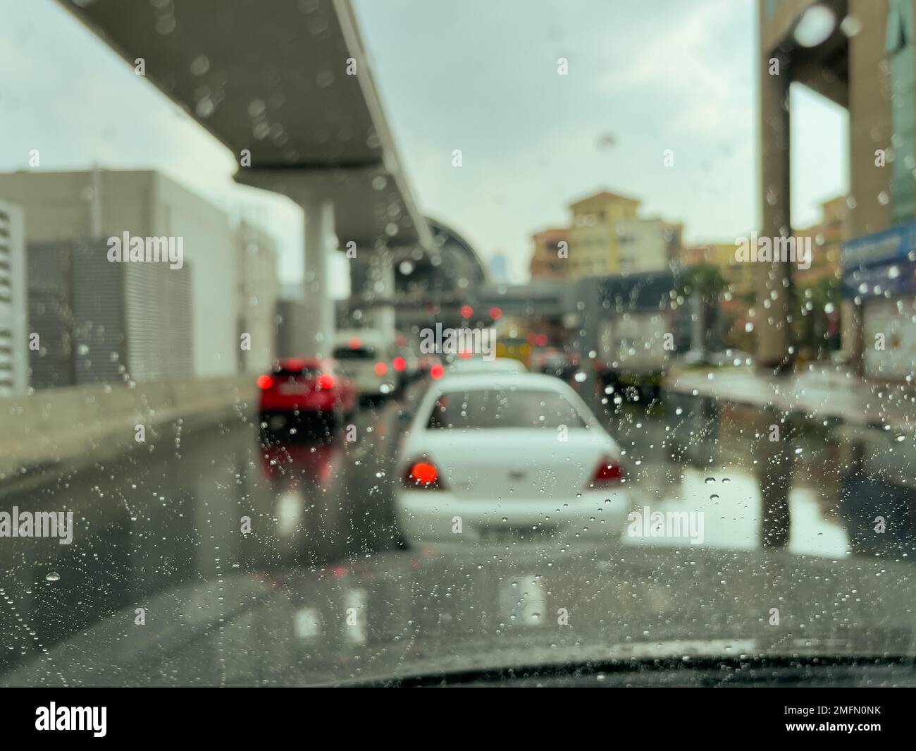 Selective focus and motion blur of raindrops on the windshield of a vehicle in heavy slow moving ...