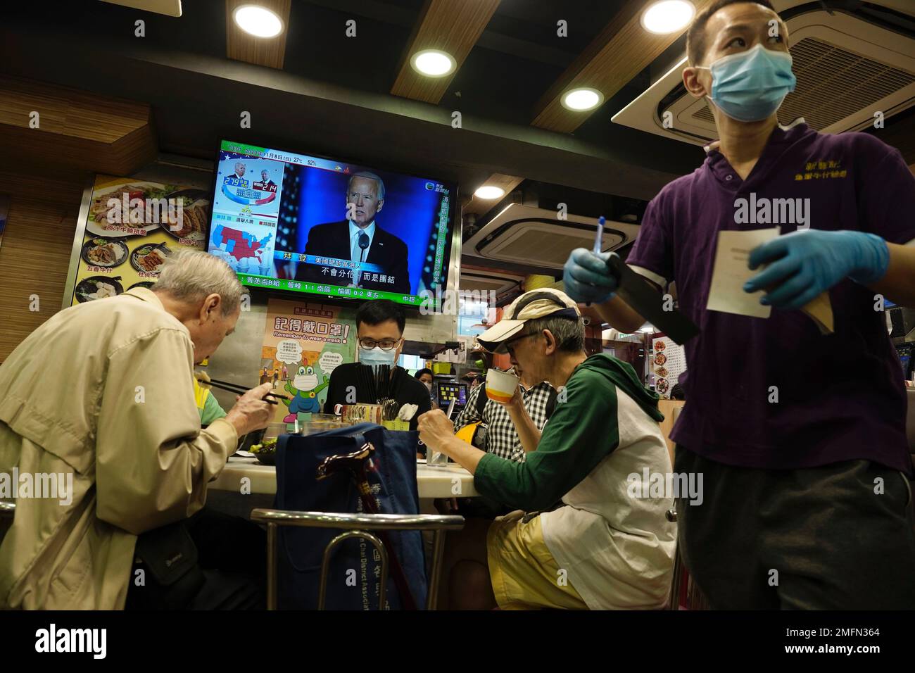 A TV screen shows a broadcast of President-elect Joe Biden speaking, at ...