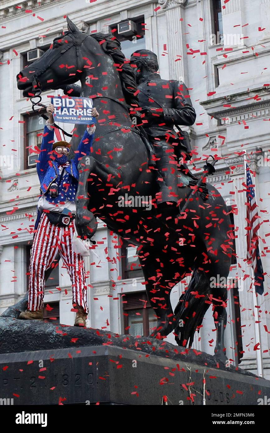 A man dressed as Uncle Sam celebrates atop the statue of Civil War ...