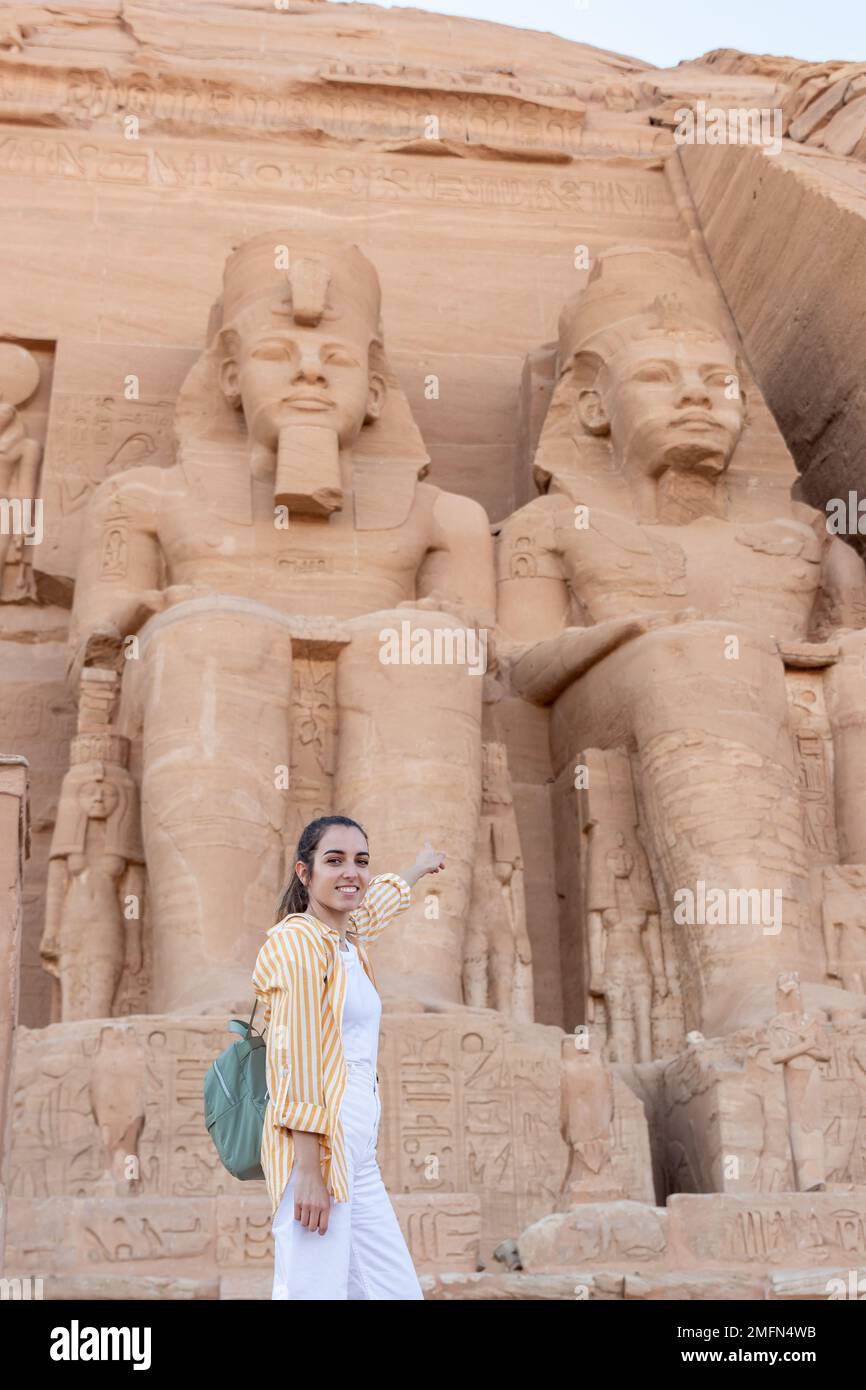 Vertical photo of young tourist woman pointing Abu simbel temple from ...