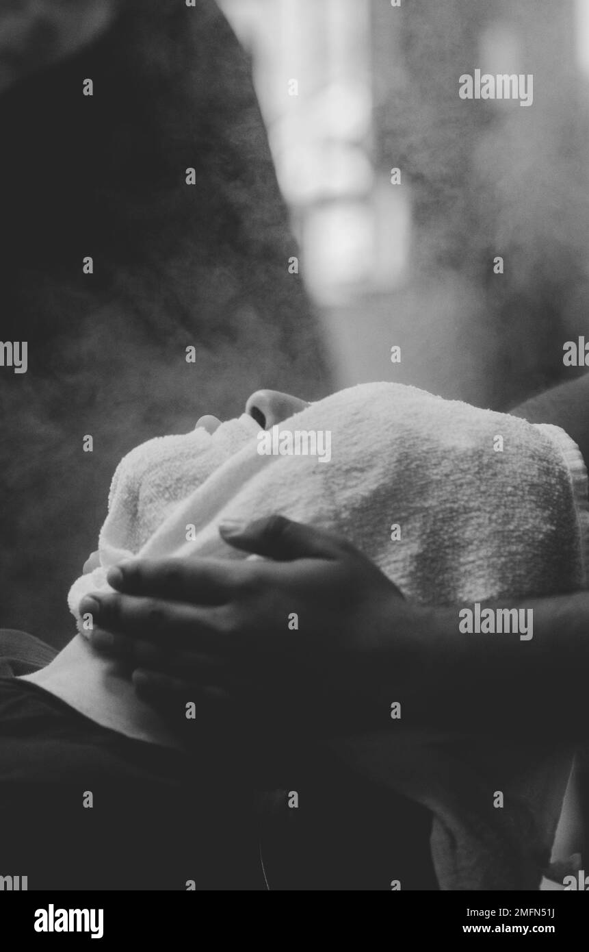 Young Caucasian man getting beauty treatment with steam towel at a ...