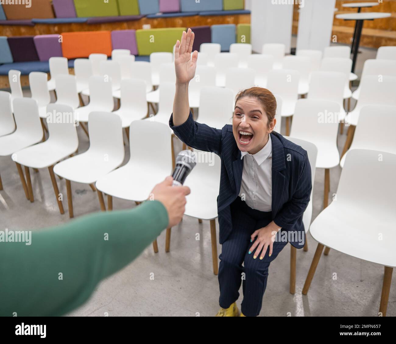 A red-haired Caucasian business woman sits in the front row in an empty ...