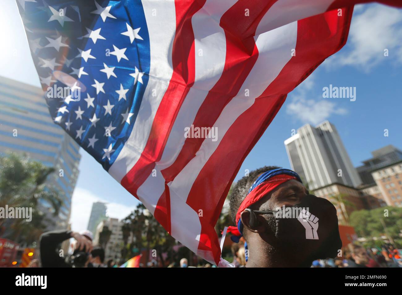 A man carries a flag as people march in Los Angeles, Saturday, Nov. 7 ...