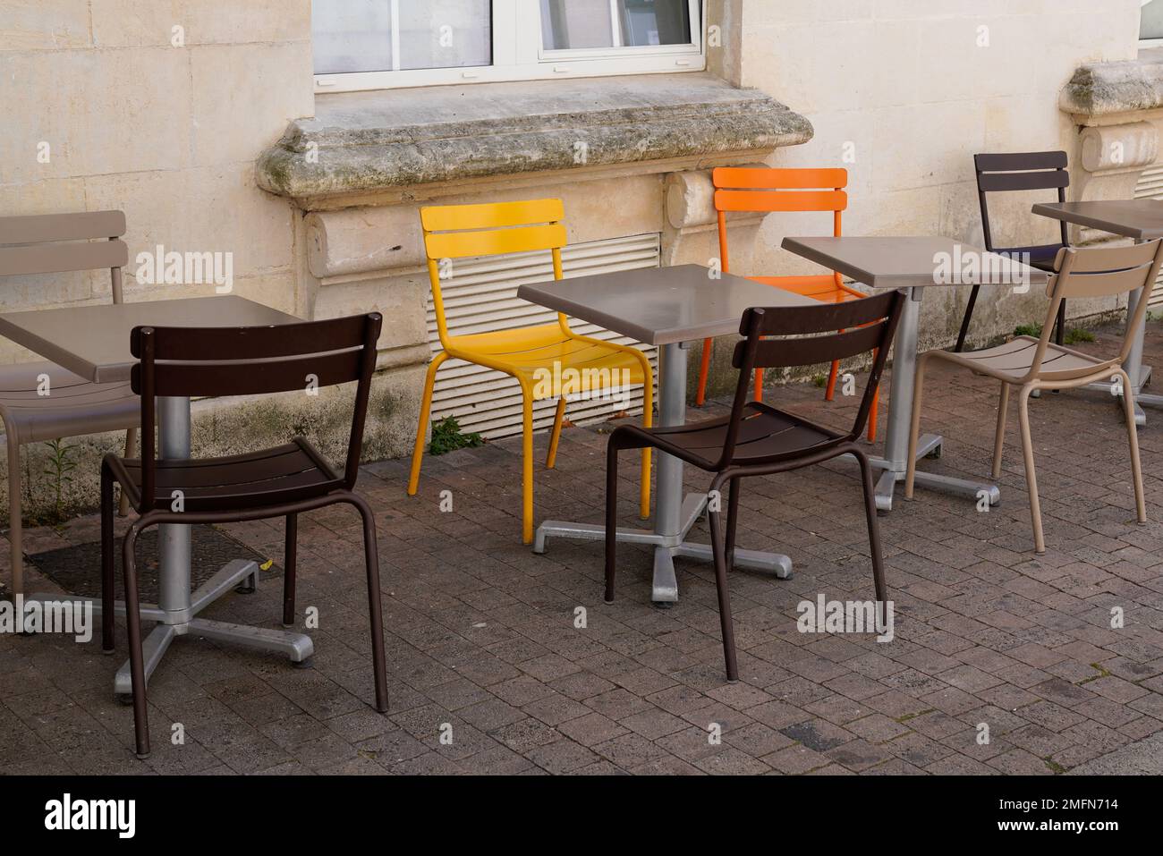 metal chairs and tables in the street facing the restaurant bar terrace ...