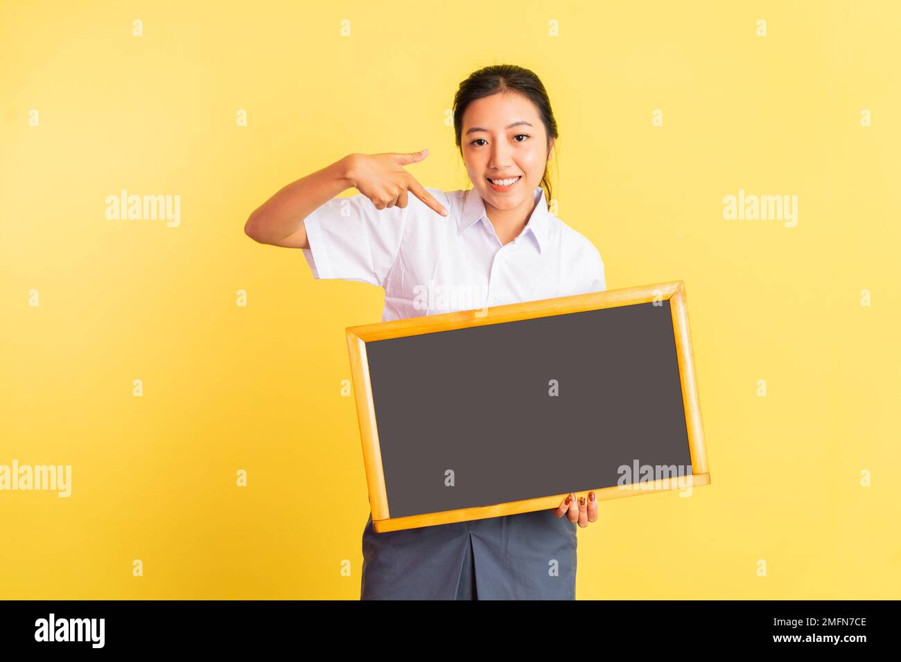 girl in high school uniform holding blackboard with pointing finger ...