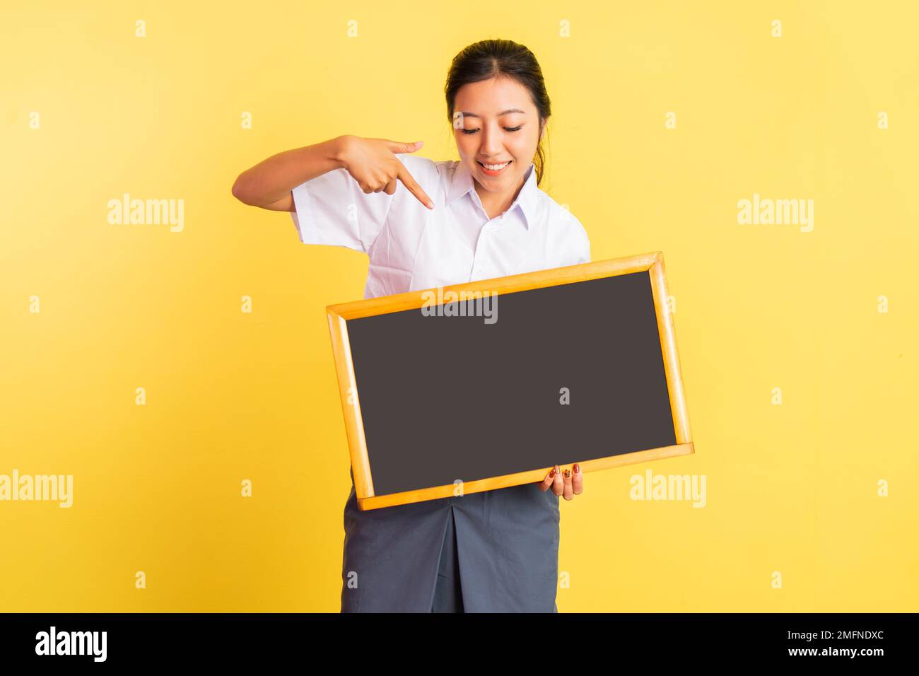 girl in school uniform holding black chalkboard with finger pointing ...