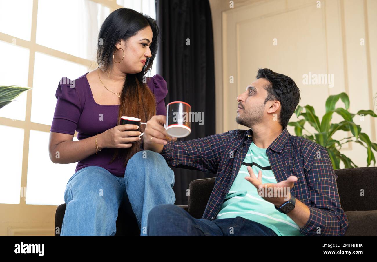 Happy smiling young couple having tea or coffee while talking each ...