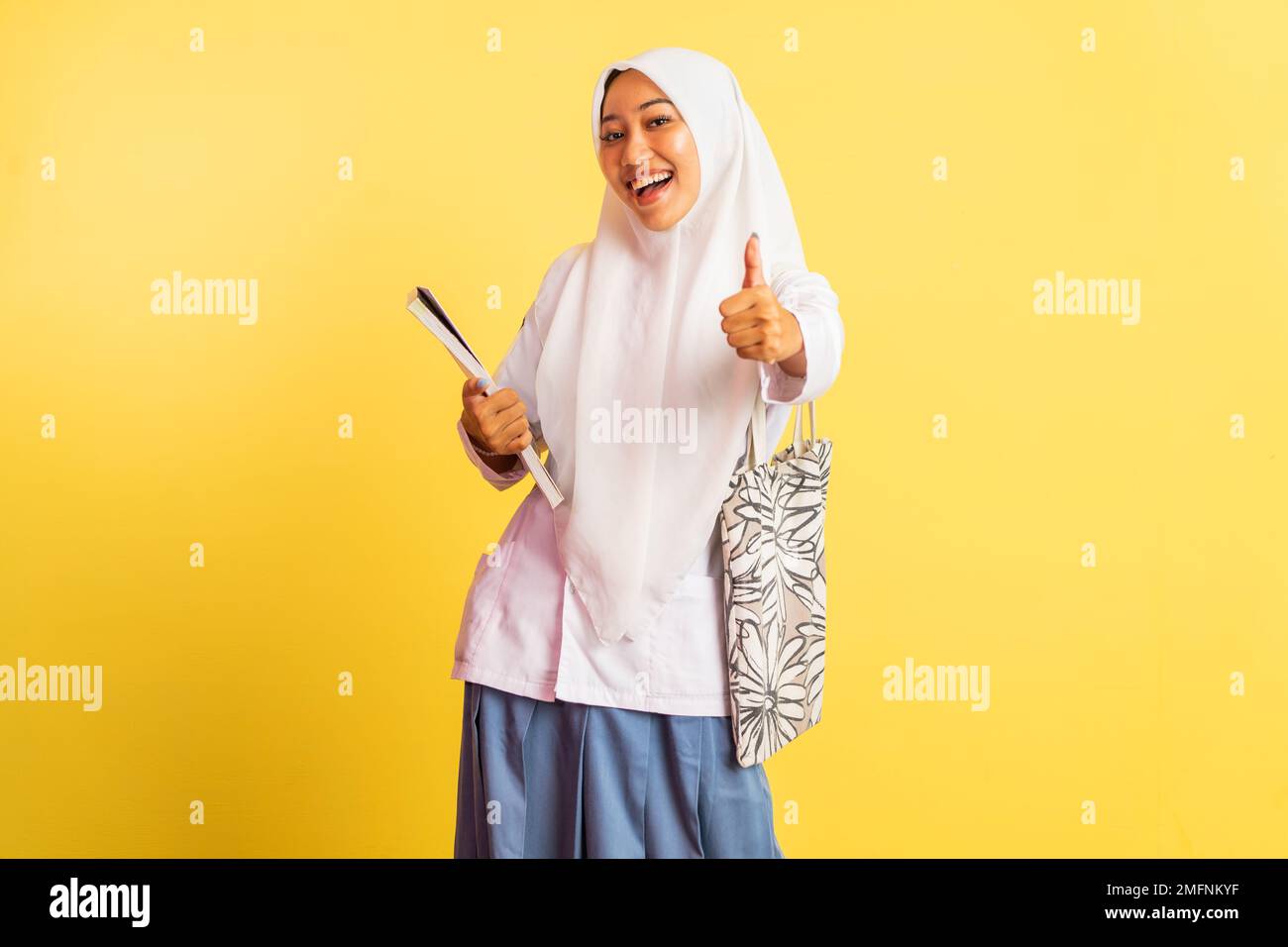 happy veiled student girl carrying book with thumbs up Stock Photo - Alamy