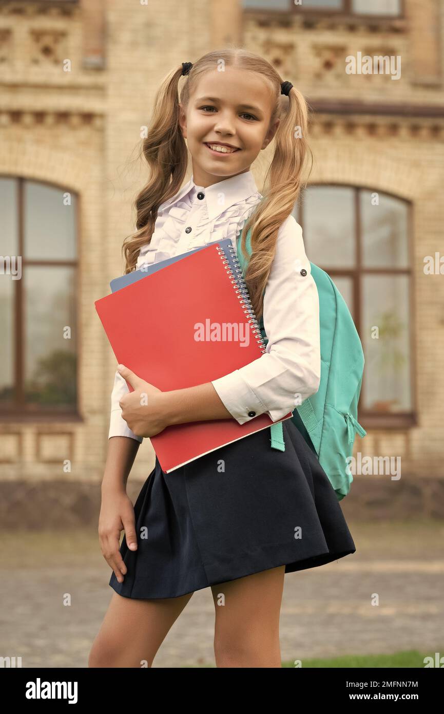 Happy kid in uniform back to school carrying books and backpack ...