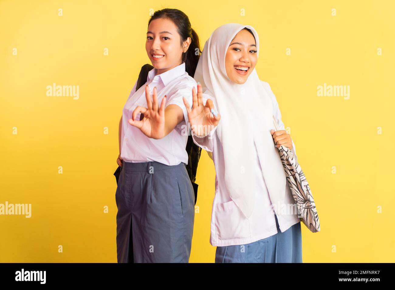two high school girls carrying bags with ok hand gestures Stock Photo ...
