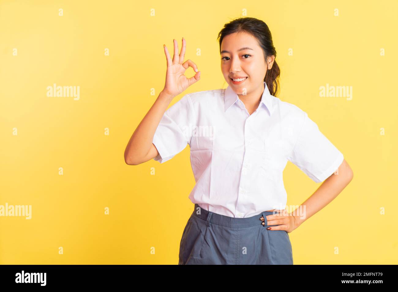 teen asian girl in uniform standing with okay hand gesture Stock Photo ...
