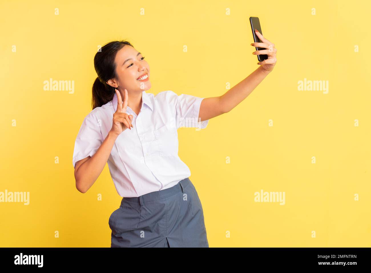 girl school selfie using handphone with v sign hand gesture Stock Photo ...
