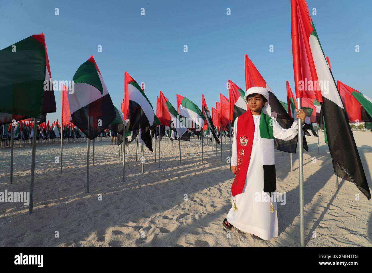 An Emirati boy poses for his mother among UAE national flags set up to ...